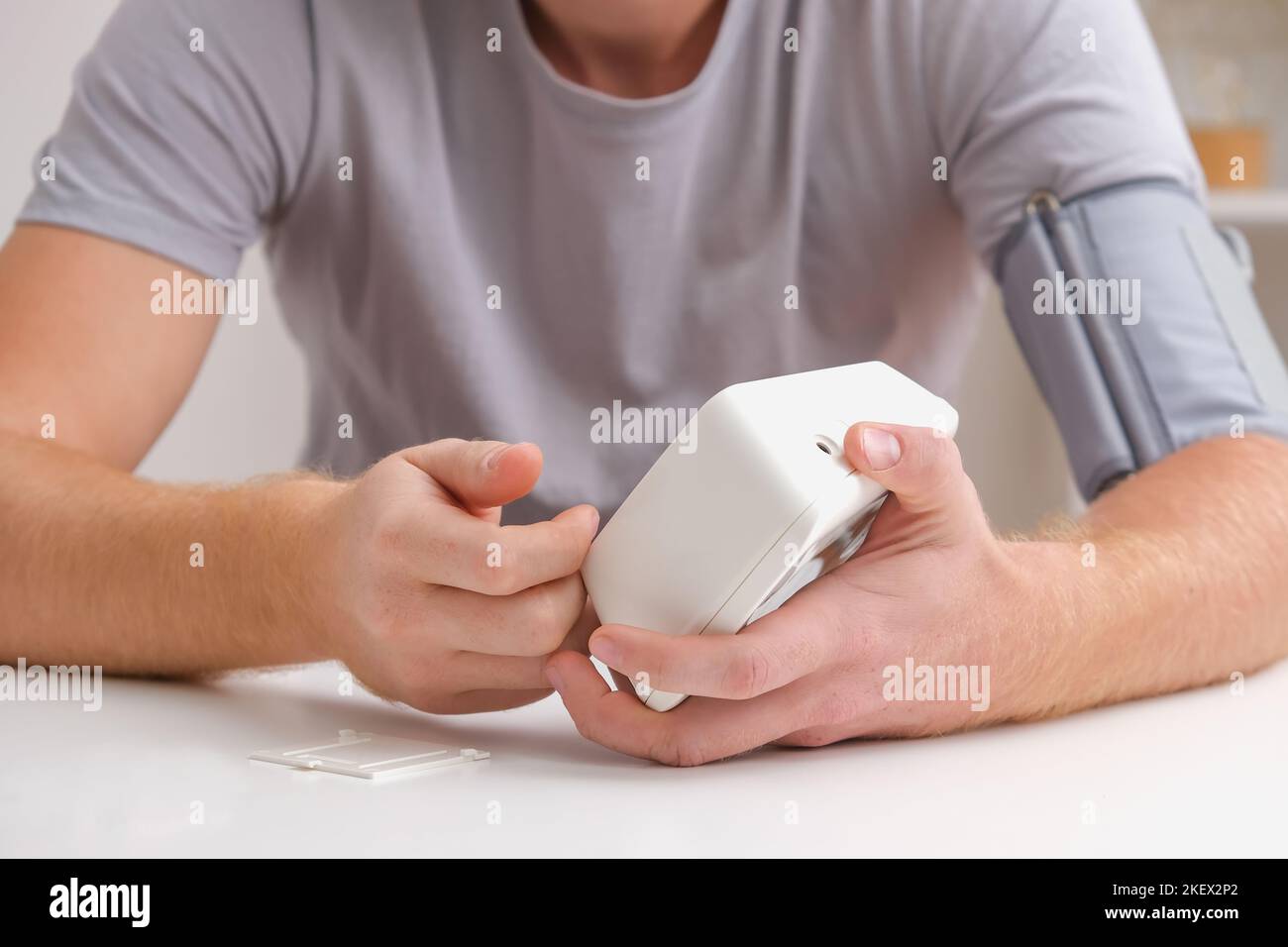 A man measures blood pressure with a white electric tonometer lying on ...
