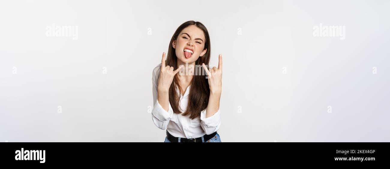 Rock n roll. Young woman showing rock on, heavy metal sign, having fun ...