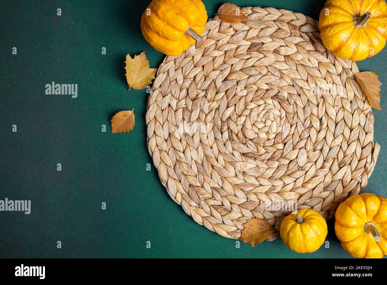 Cozy hygge table. Top view of wicker place mat, pumpkins, autumn leaves ...