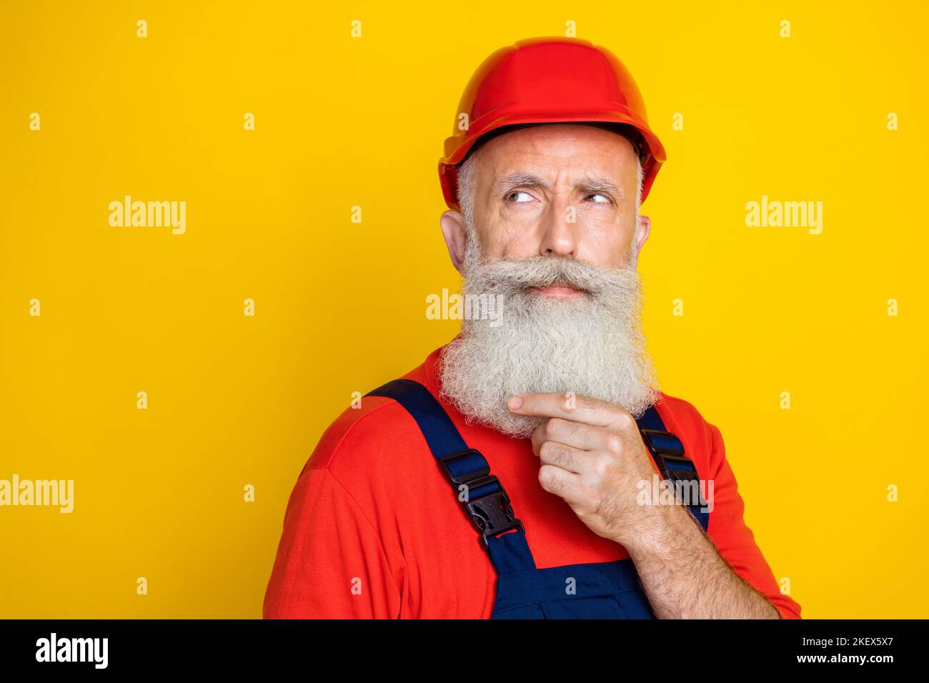 Photo of serious dreamy senior guy dressed uniform overall red hardhat ...