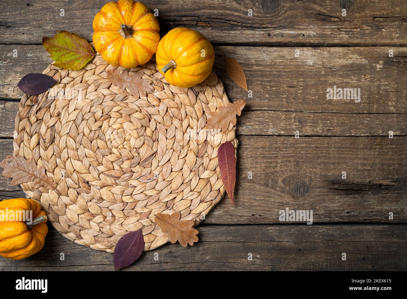 Cozy hygge table. Top view of wicker place mat, pumpkins, autumn leaves ...