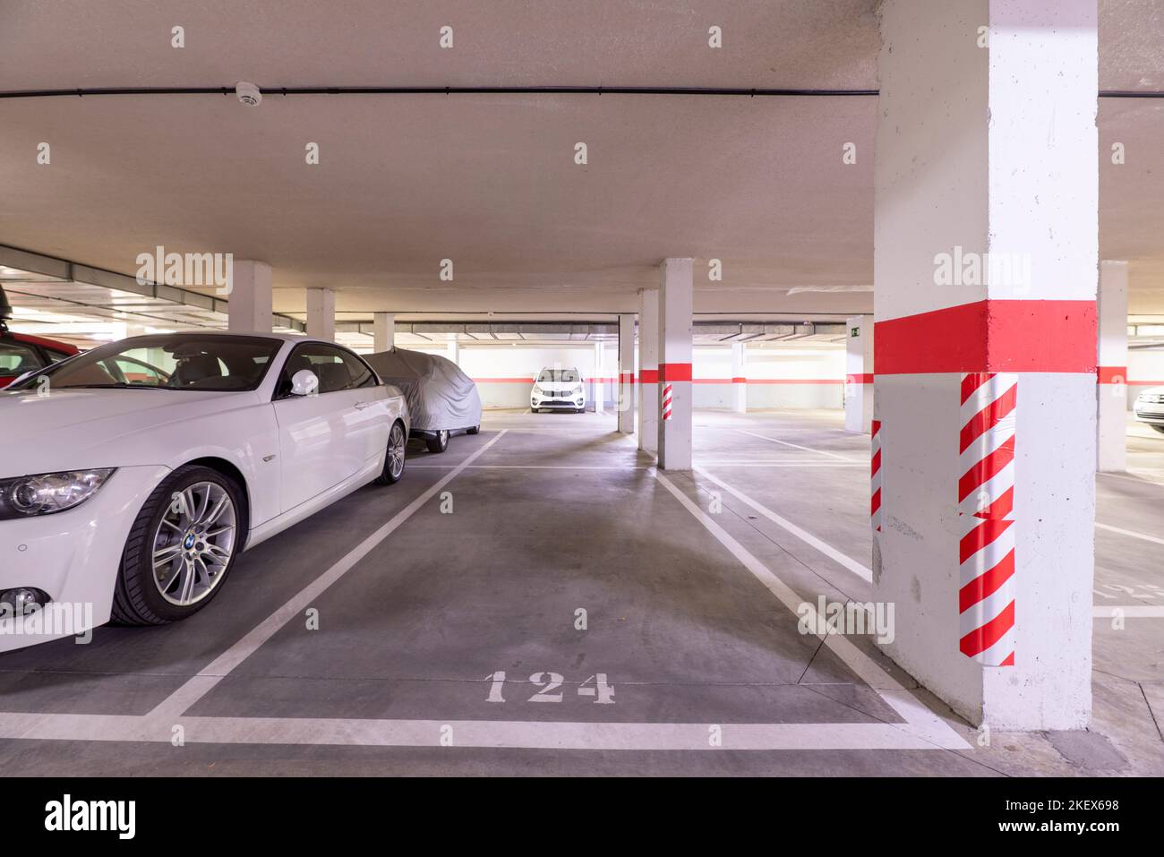 A garage with parked cars, free spaces and columns with warning signs ...