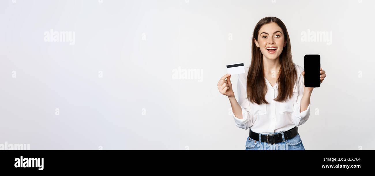 Happy woman showing credit card and smartphone screen, concept of ...