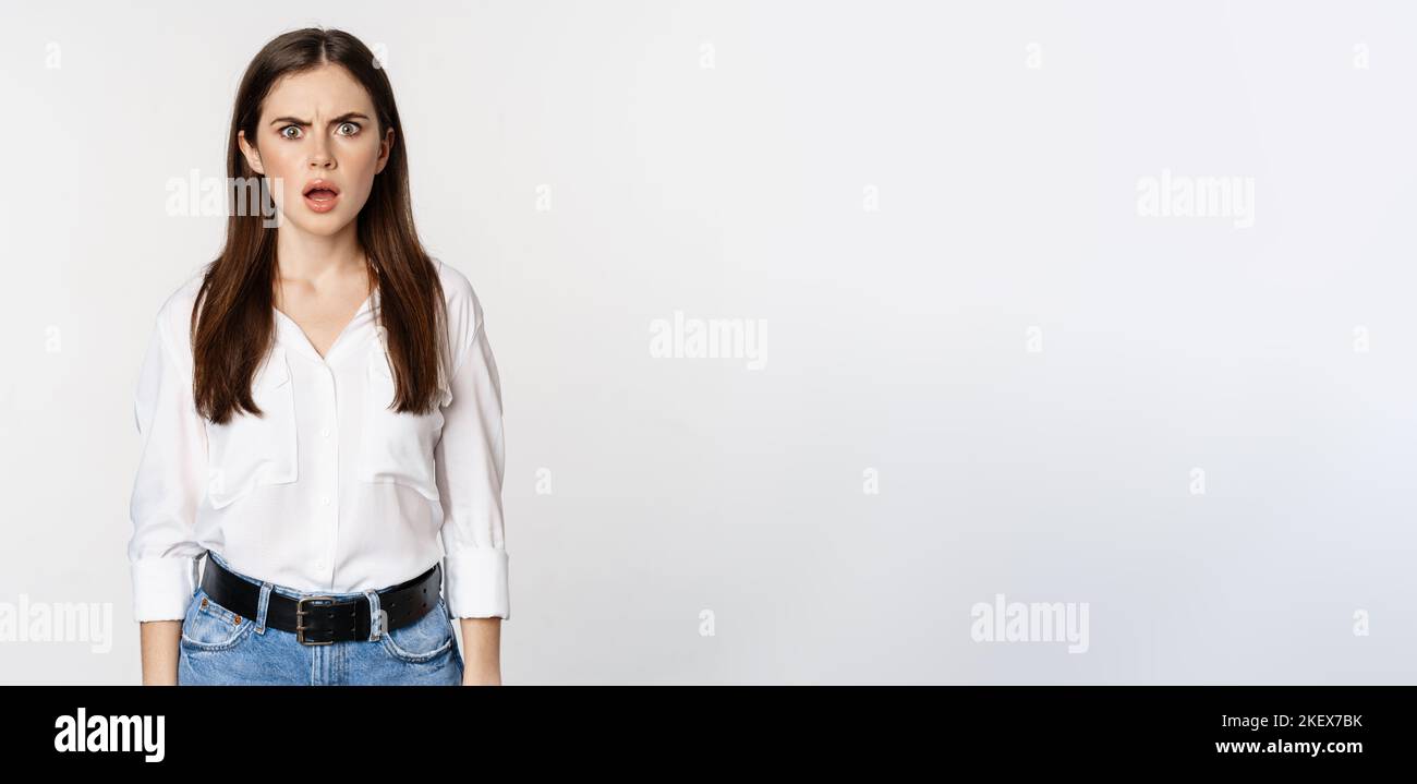 Confused businesswoman frowning, drop jaw and staring puzzled at camera ...