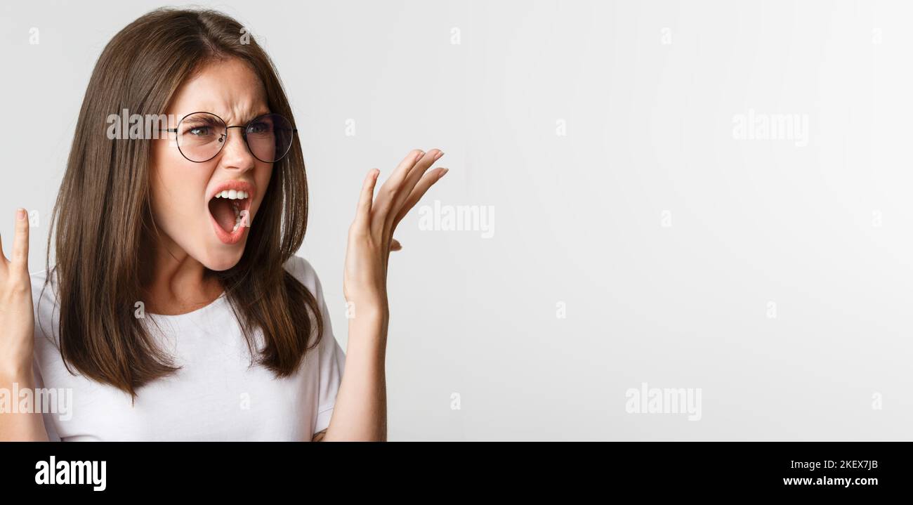 Close-up of angry and outraged beautiful woman in glasses yelling and ...