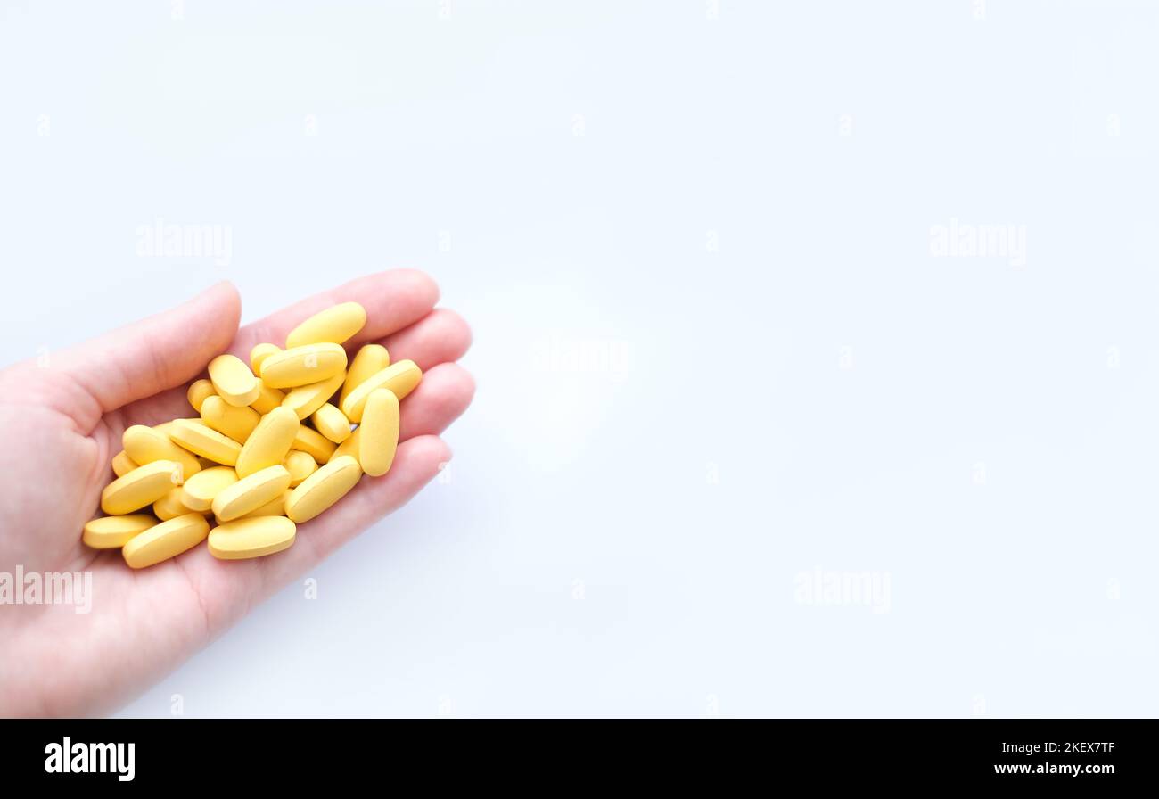 Close-up texture of yellow multivitamin tablets in female hand on white ...