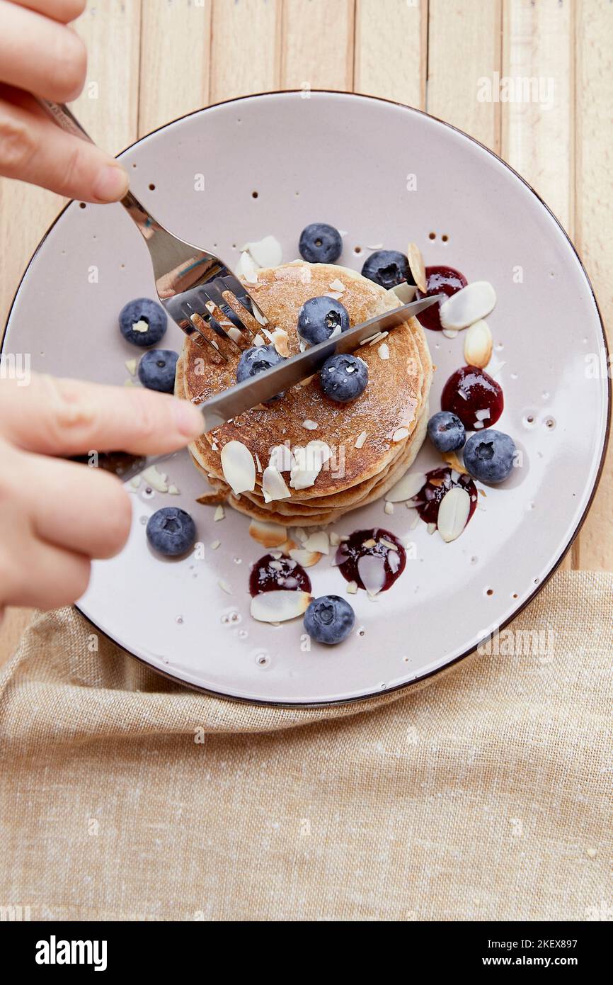 Woman holds cutlery while having breakfast - fresh pancakes with fresh ...