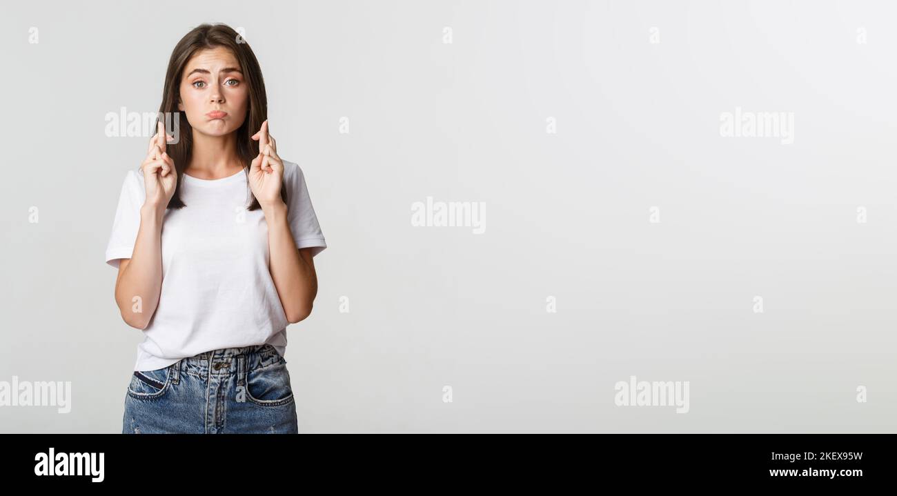 Hopeful cute brunette girl cross fingers good luck, making wish or ...