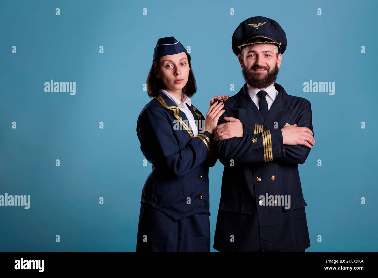 Smiling airplane aviator and stewardess couple in uniform looking at ...