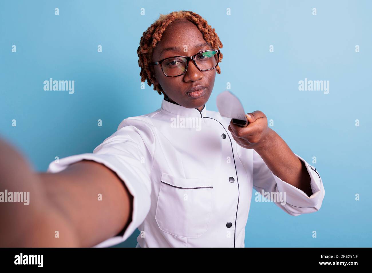 African american female chef making selfie holding sharp knife with ...