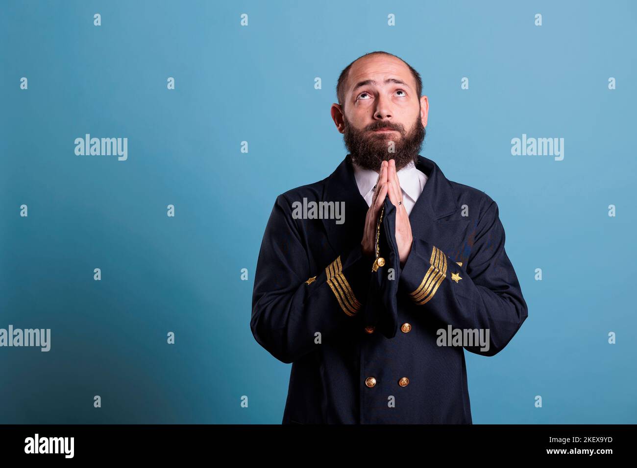Airline pilot in aviation uniform praying to gods with closed eyes ...