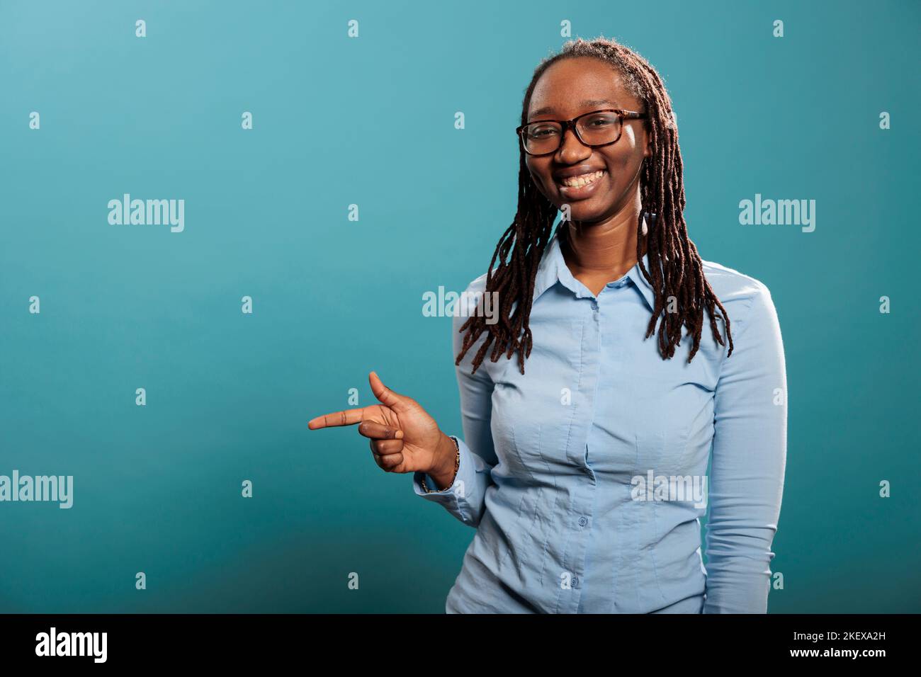 Happy excited young woman smiling heartily while pointing finger to ...
