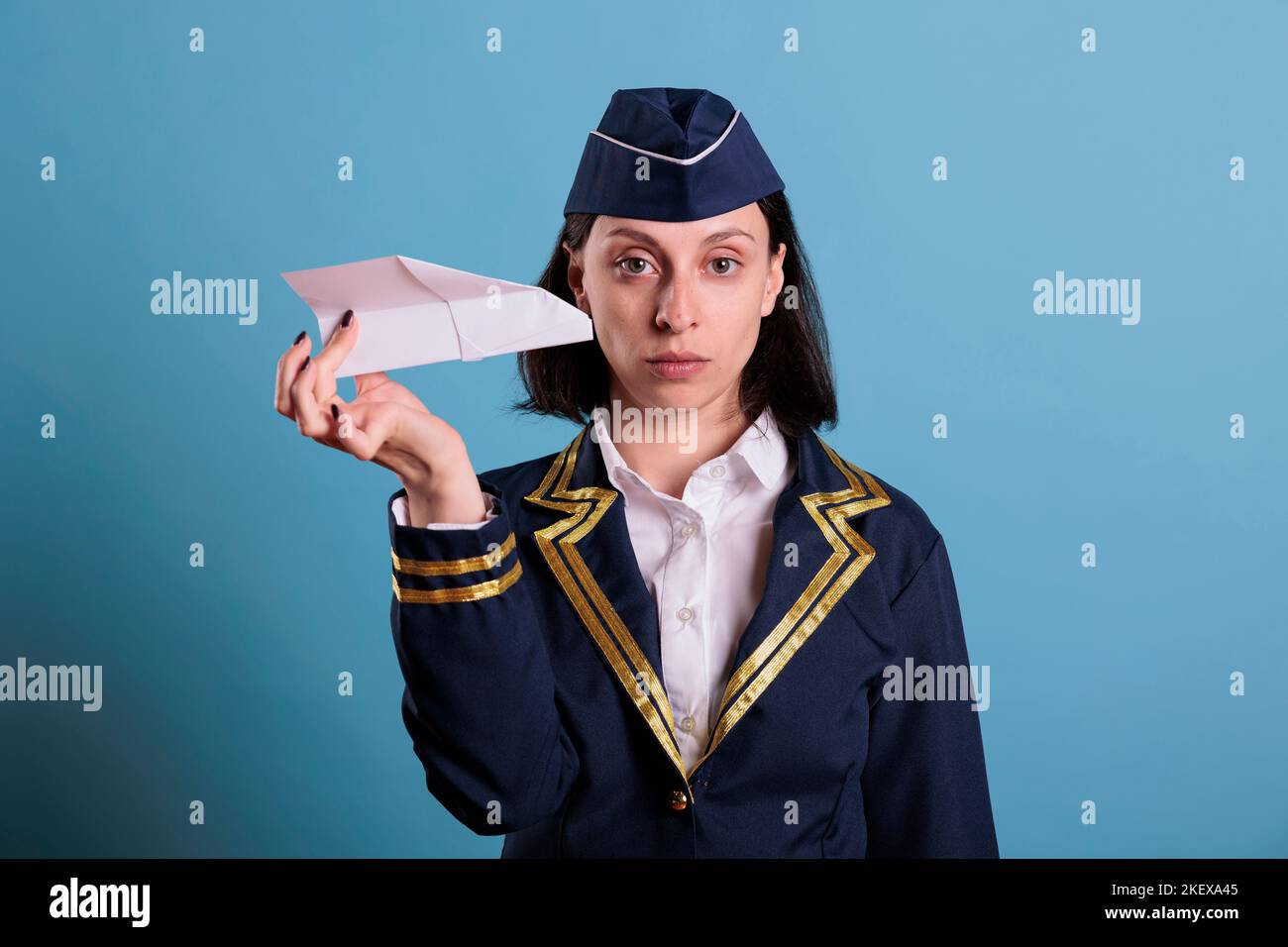Stewardess holding paper plane, looking at camera, aviation academy ...