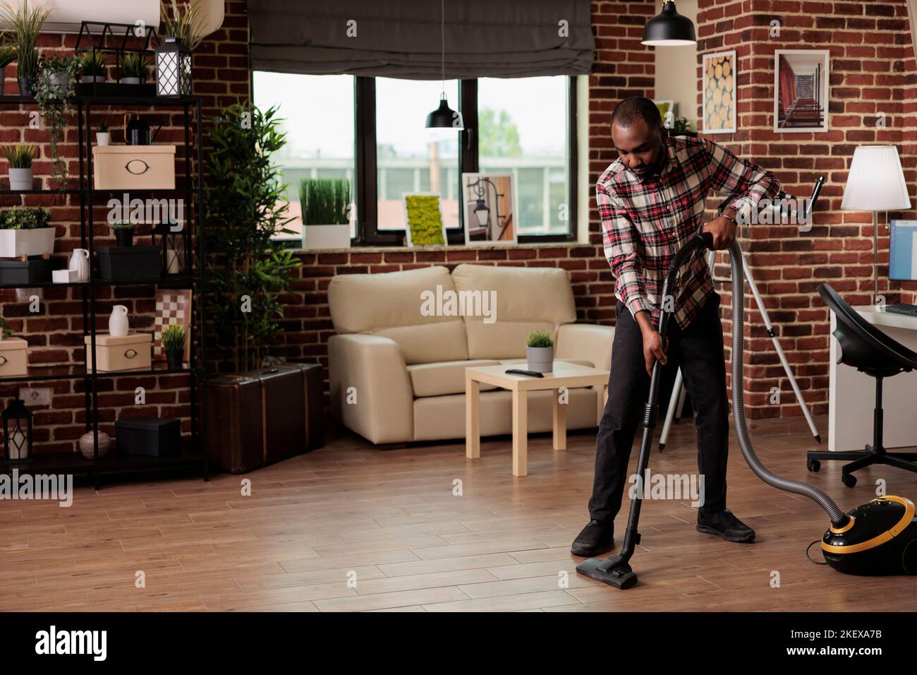 Single African American man doing house cleaning, concentrating while ...