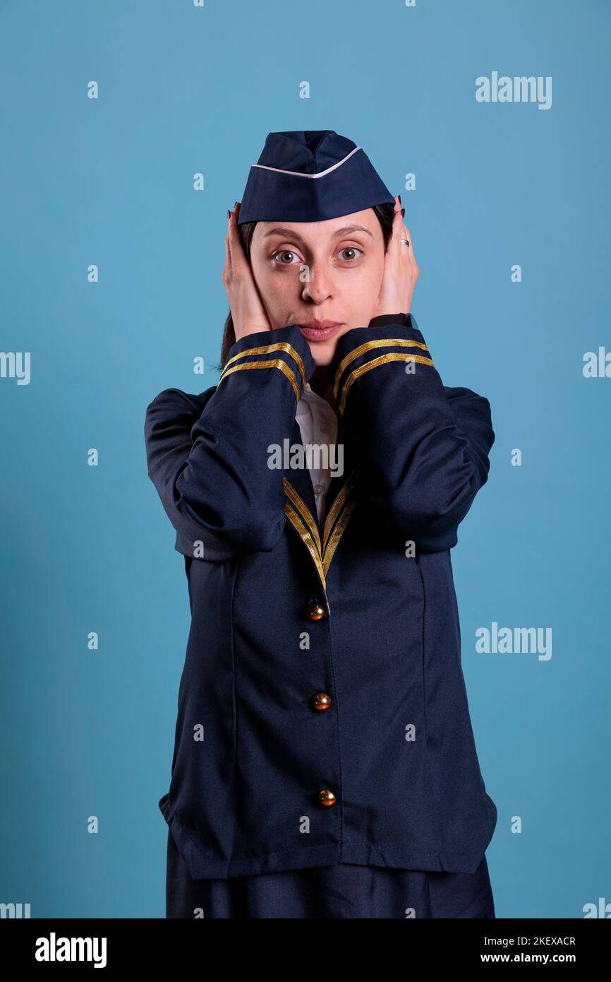 Flight attendant covering ears with hands, showing hear no evil gesture ...