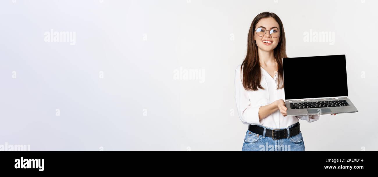Young woman in glasses showing laptop screen, demonstrating promo on ...