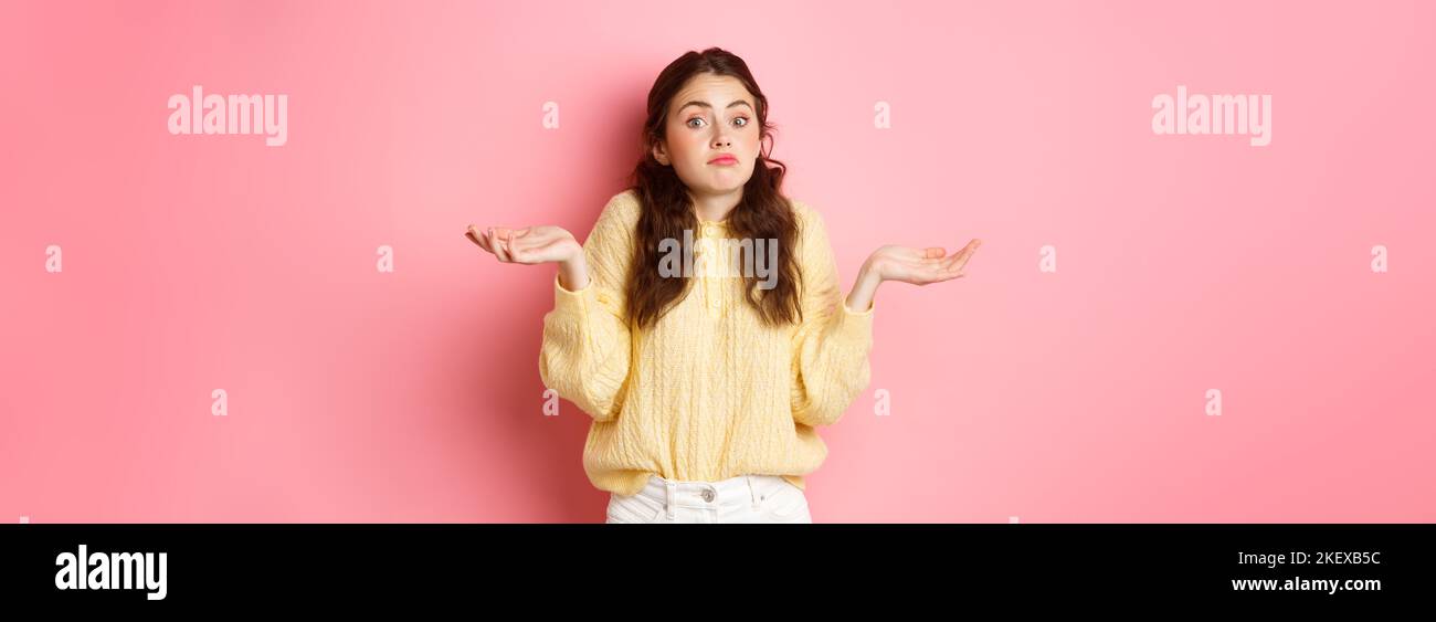 I dont know. Indecisive girl shrugging shoulders and looking unaware at ...