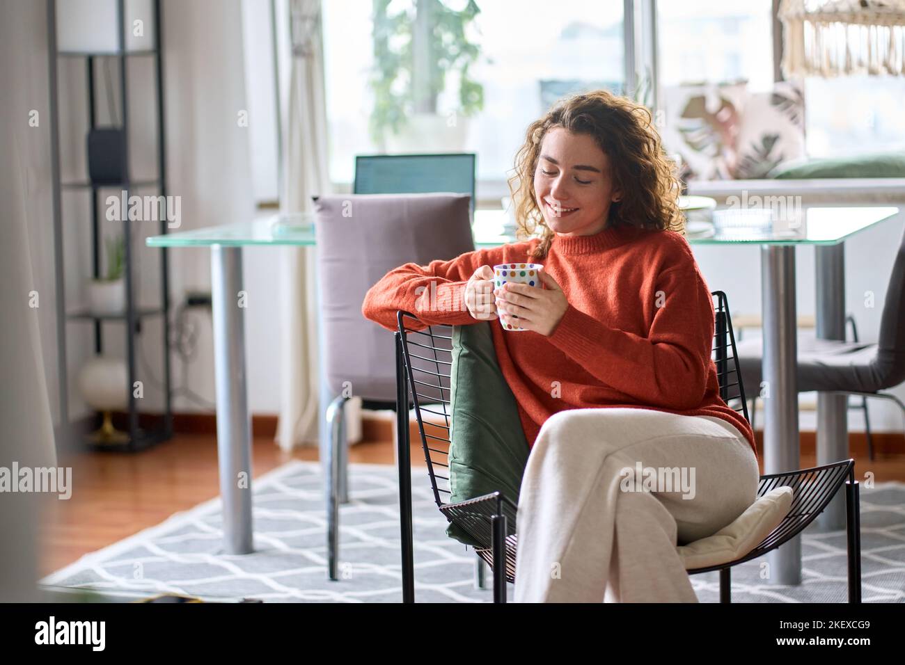 Young happy pretty woman sitting on chair drinking tea coffee relaxing ...