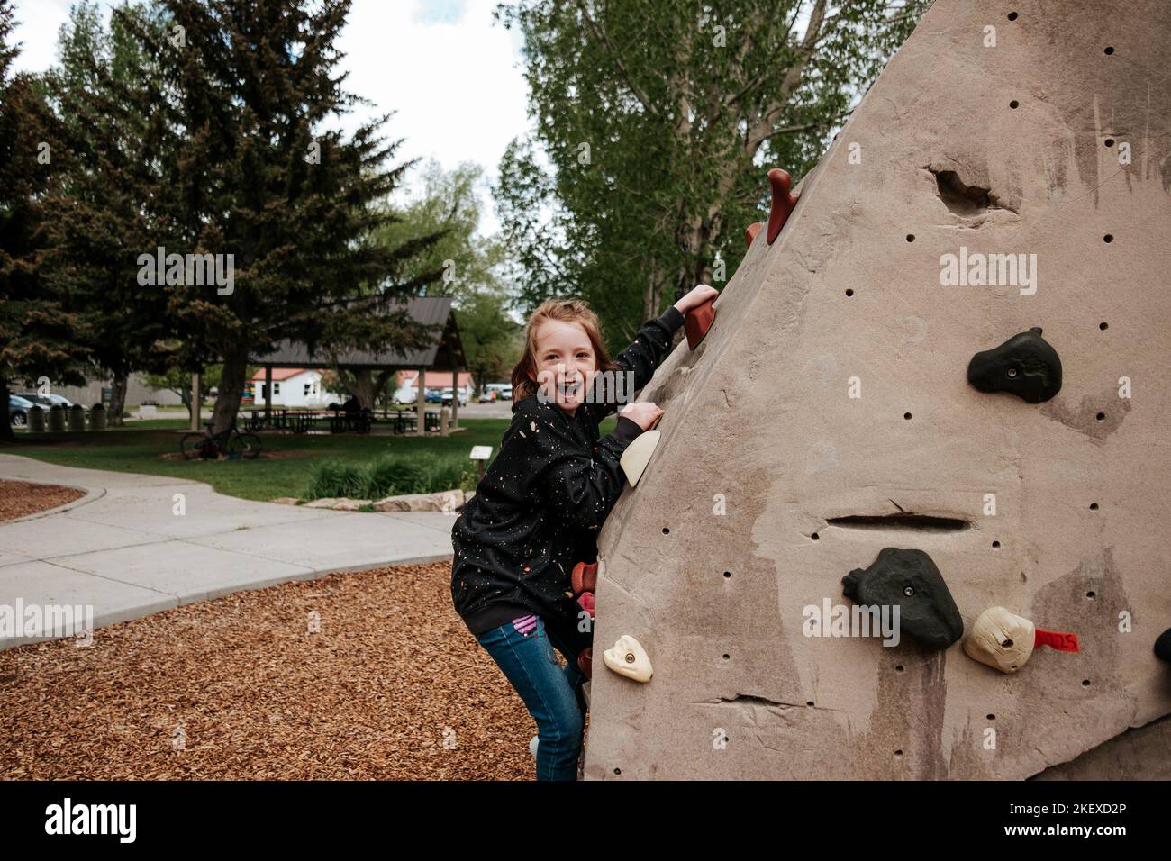 Smiling child climbing rock wall outside at a park Stock Photo - Alamy