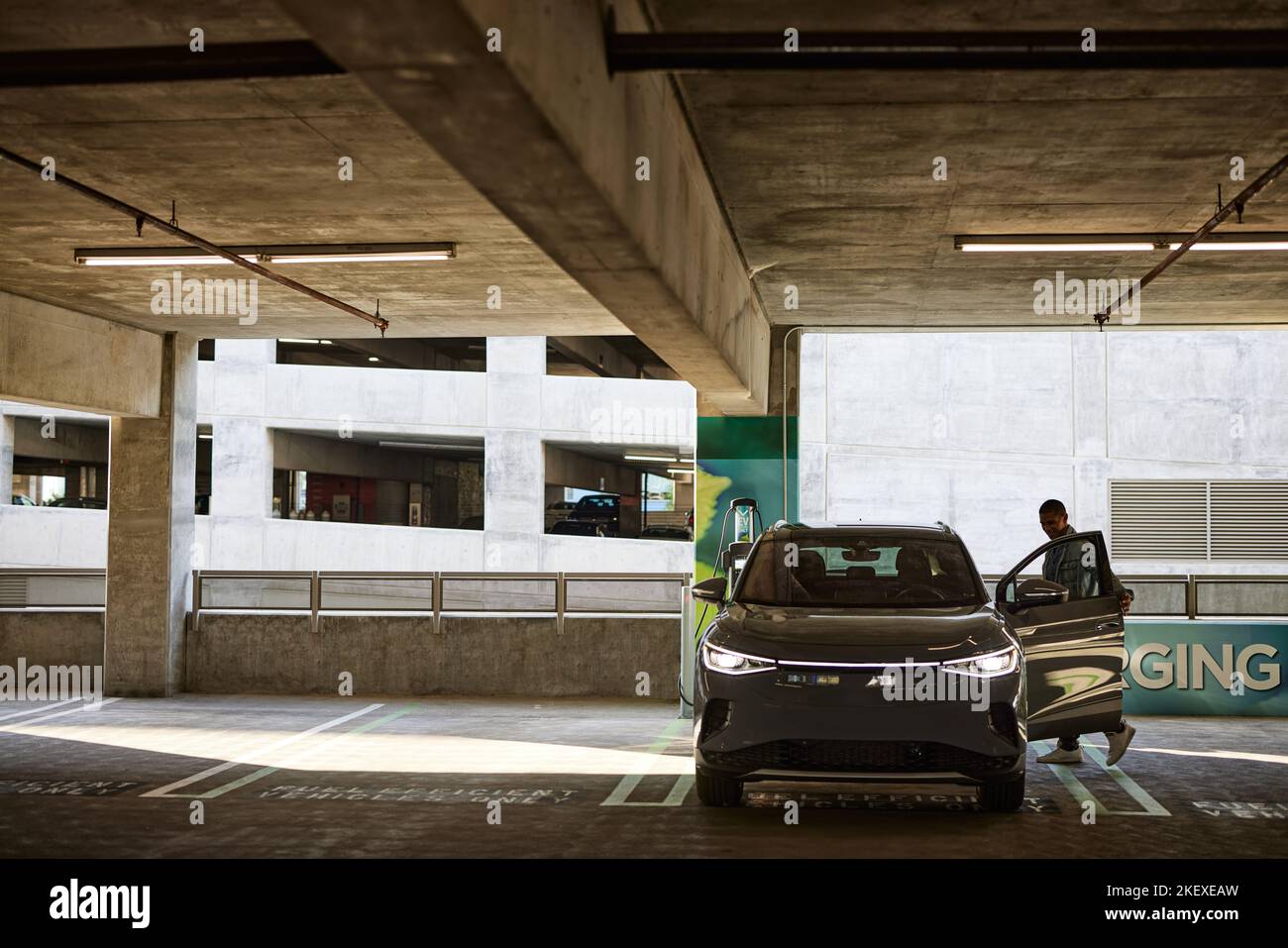 Man entering in electric car at parking garage Stock Photo - Alamy