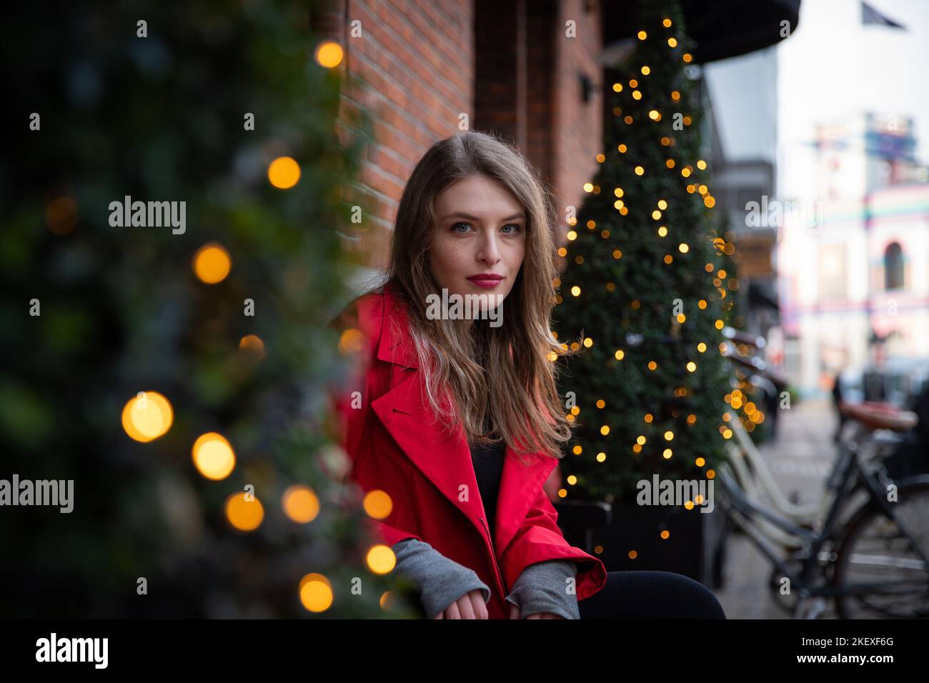 Girl sitting on a bench among decorated Christmas trees, holiday season ...