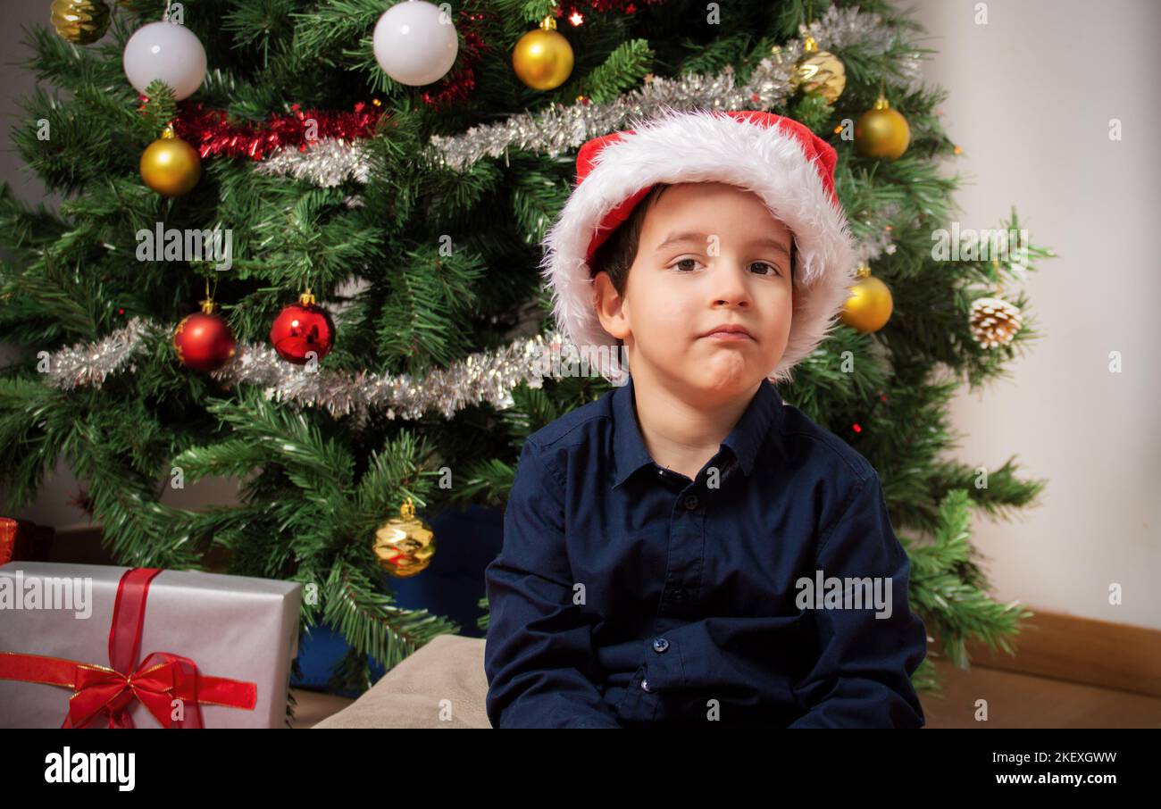 Frustrated child on christmas holiday looks at you sitting on a floor ...