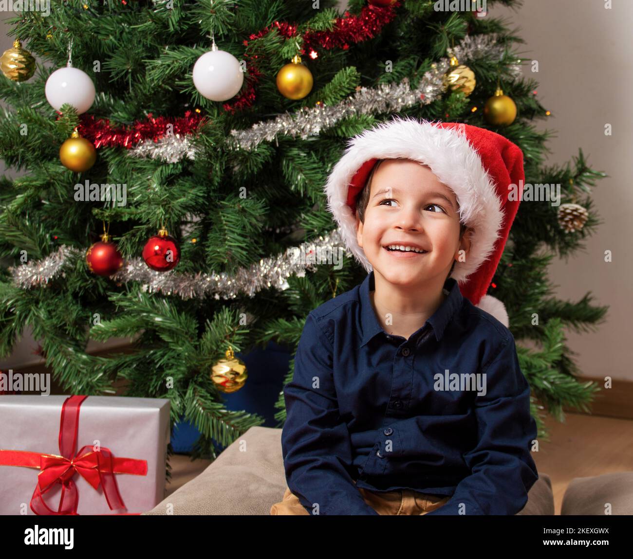 Little boy wearing santa hat smiling looking to the side and staring ...