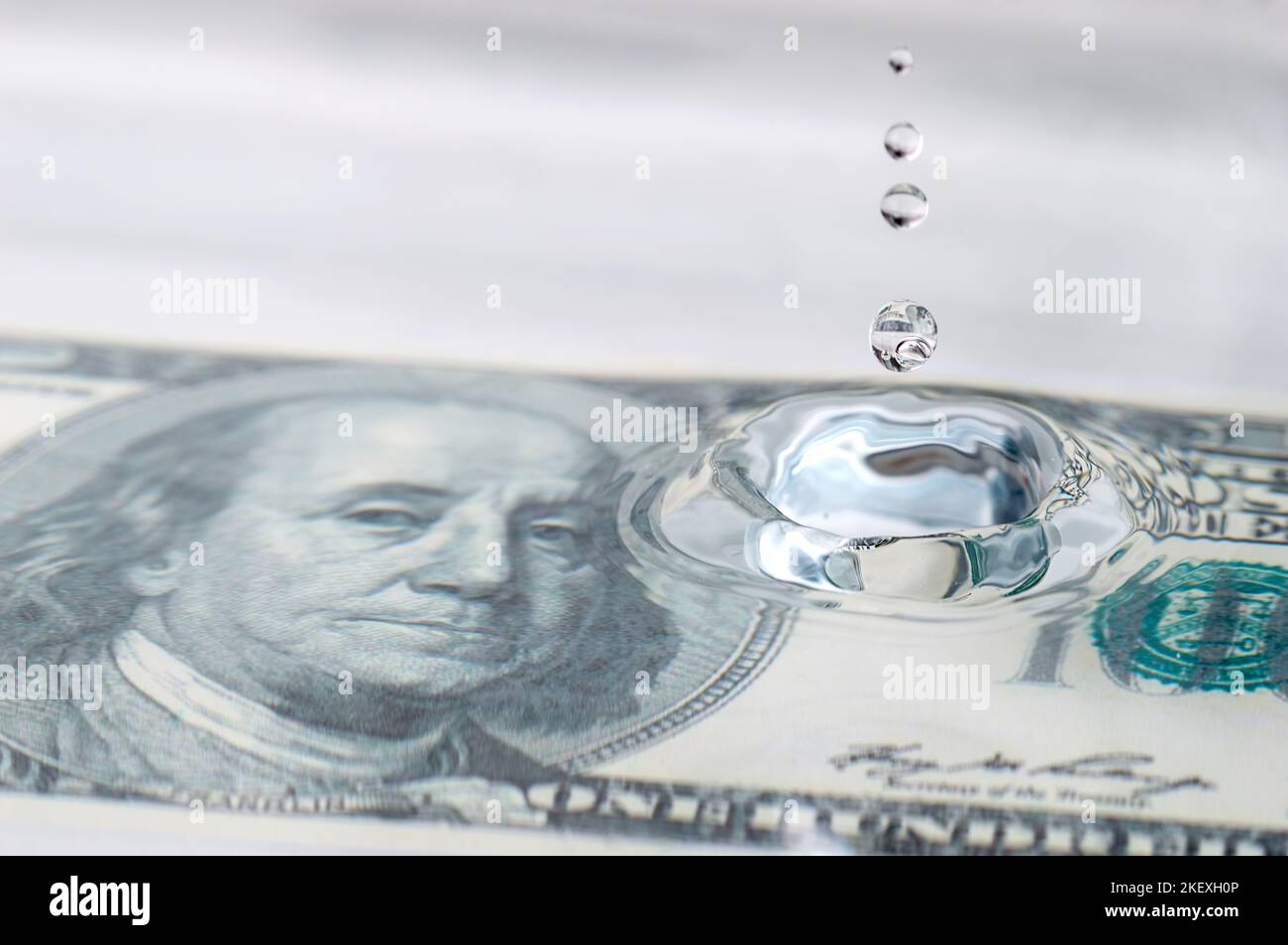 Drops of water and ripples with a hundred dollar bill growing economy ...