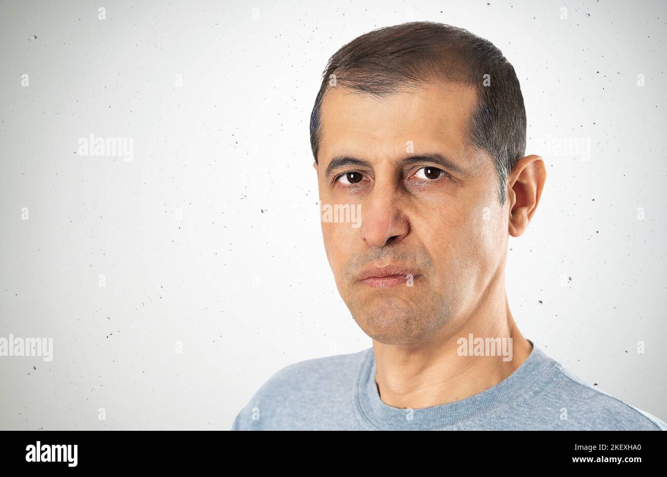 Portrait of an angry man looking at the camera with a concrete wall ...