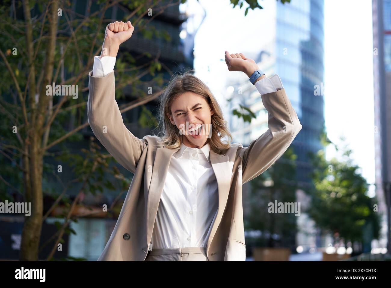 Excited businesswoman screams and celebrates, lifts hands up, does ...