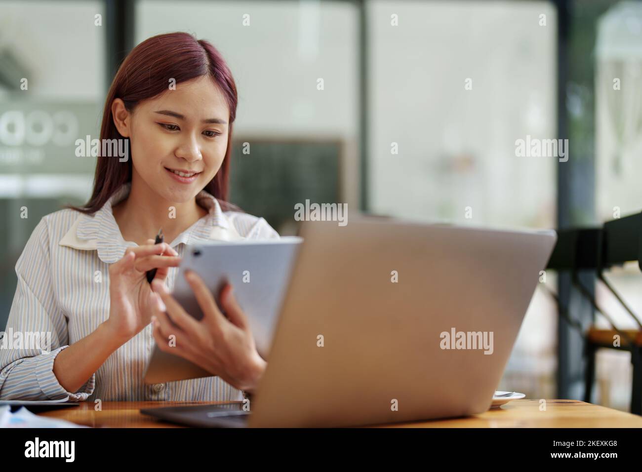 Portrait of an Asian female employee using a tablet computer at work ...