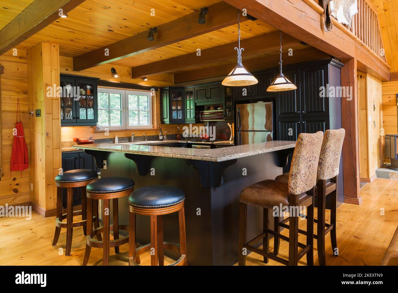 Kitchen with black wooden cabinets, island with granite countertop and ...