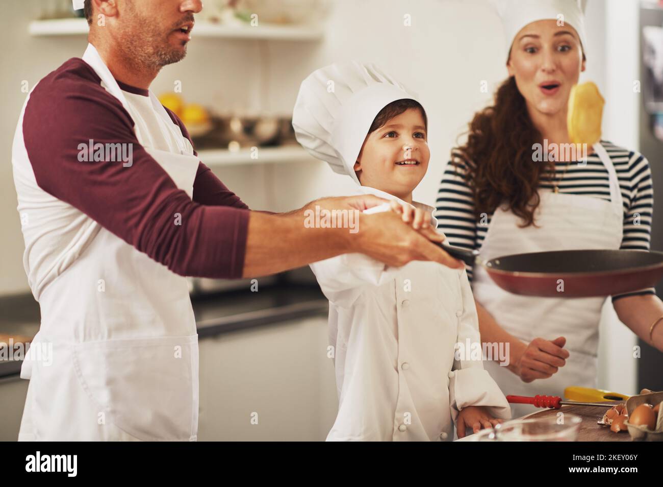 And thats how its done. a smiling family making pancakes together in ...