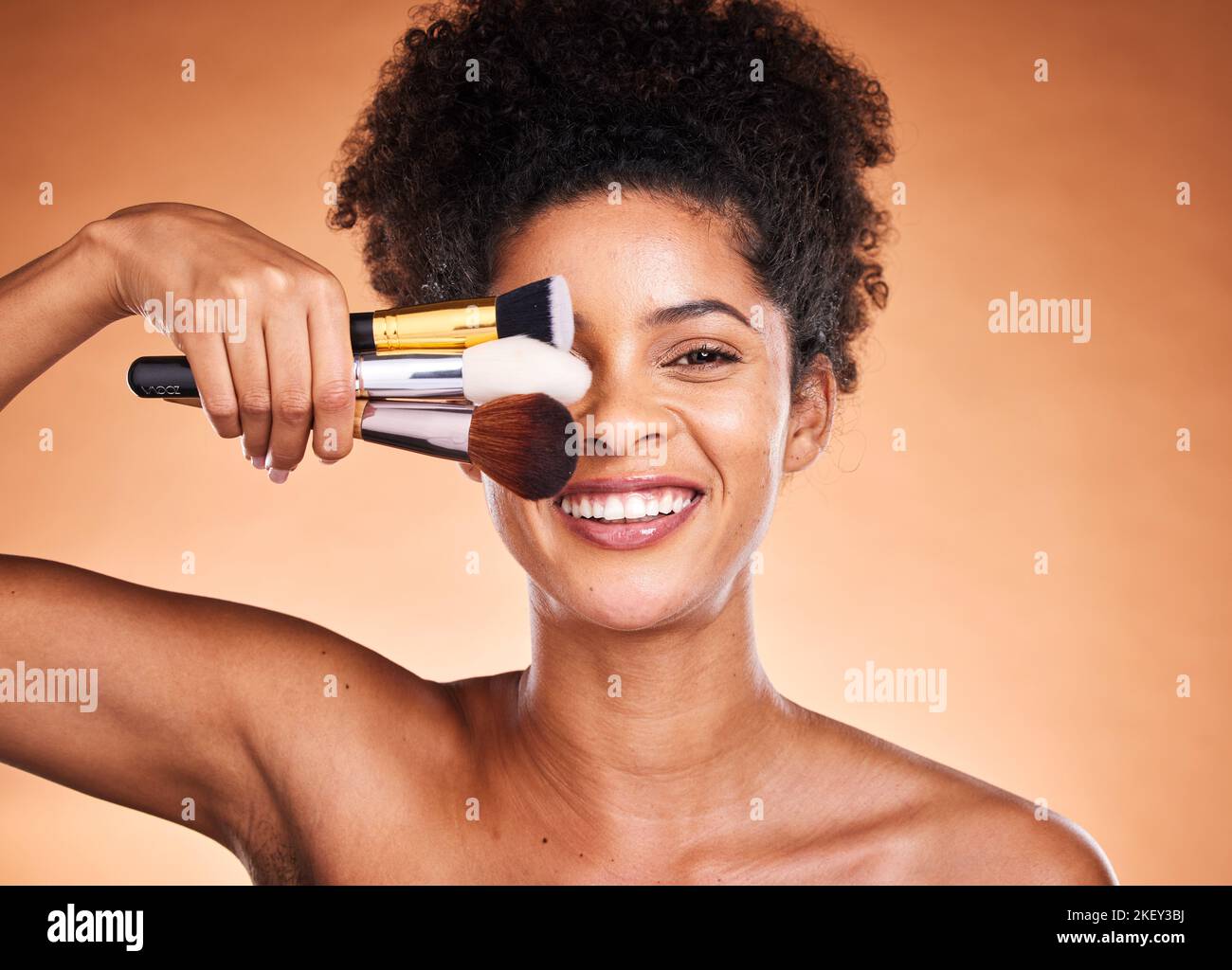 Beauty, makeup and portrait of black woman with brushes in studio ...
