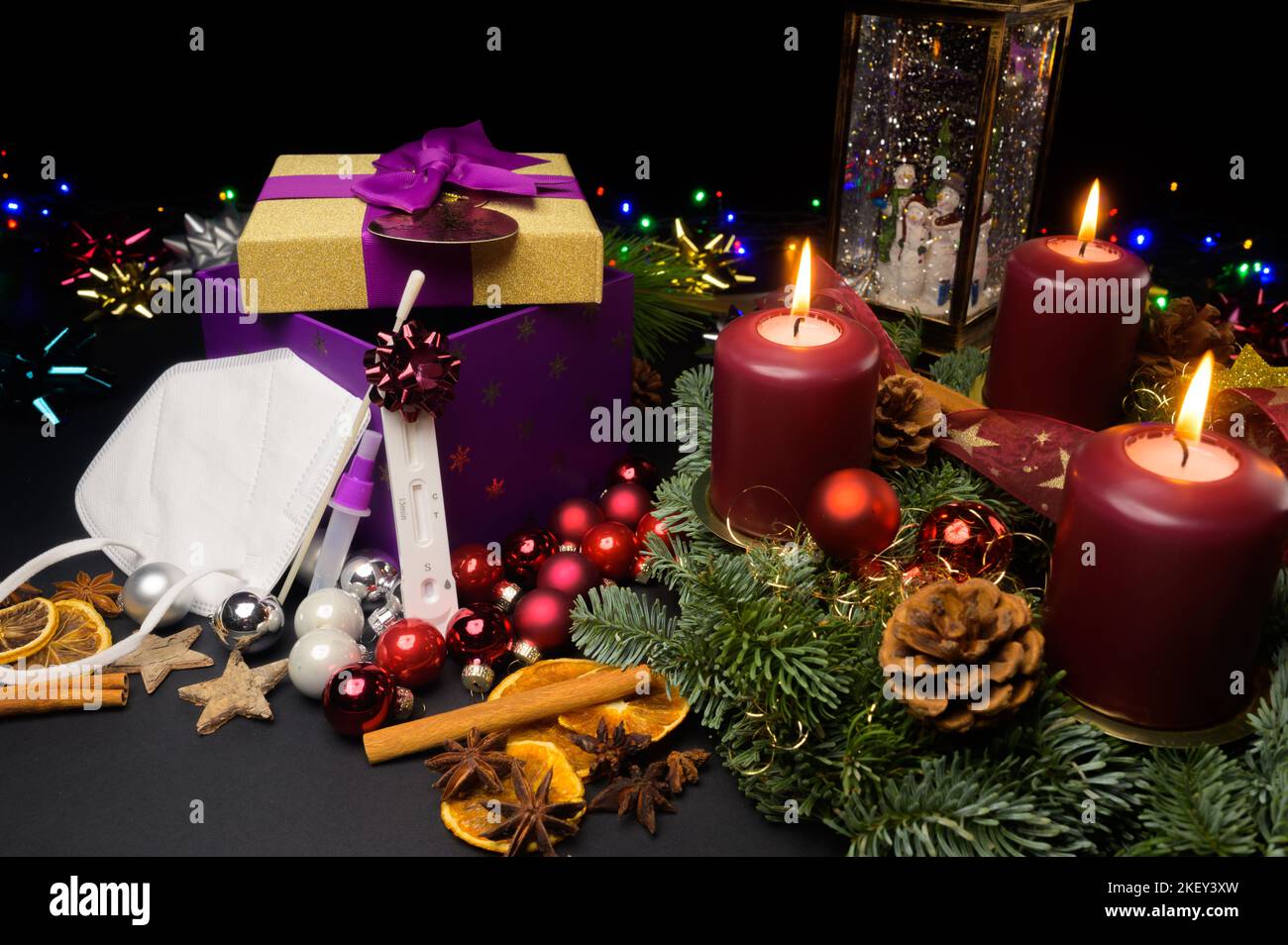 Mask and COVID test kit leaning on gift box next to advent wreath and ...