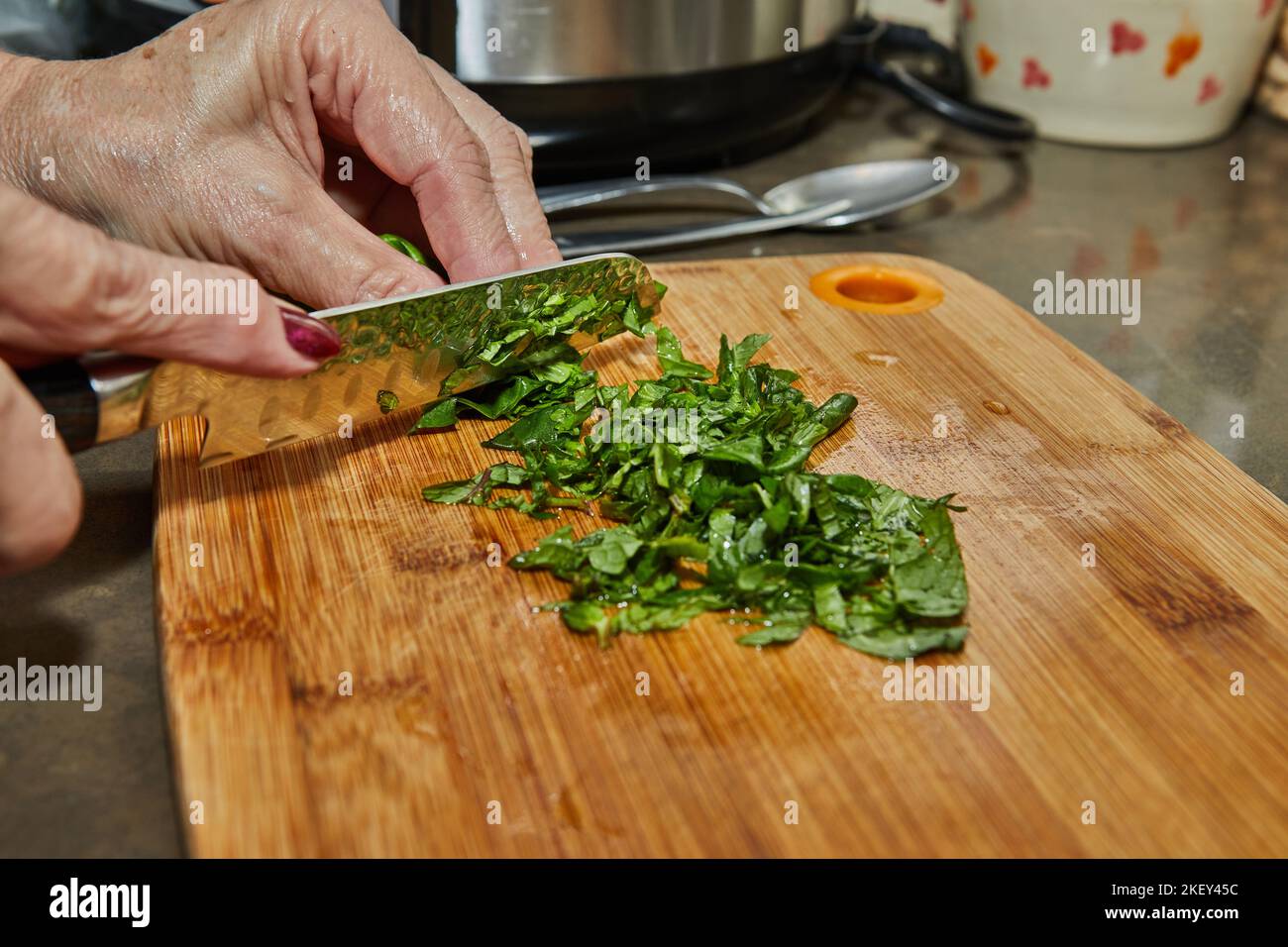 Chef cuts fresh basil leaves on a wooden board for cooking Stock Photo ...