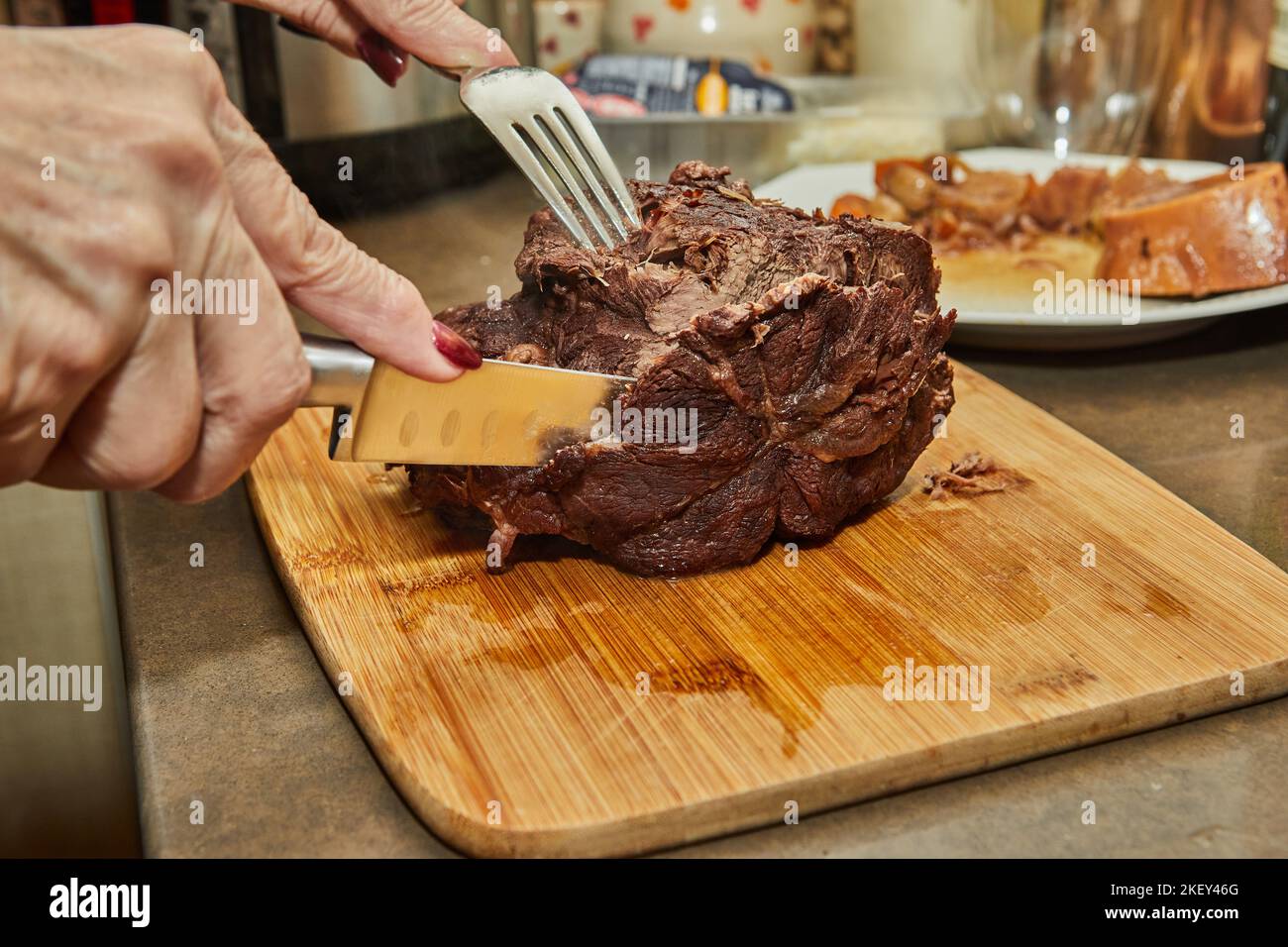 Chef cuts slices from piece of long-cooked beef Stock Photo - Alamy