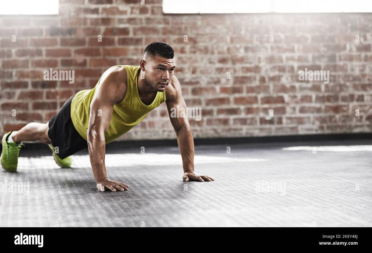 Upper body strength. Full length shot of a young man working out in the ...