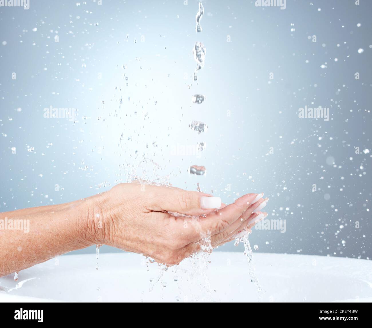 Water splash, studio and woman cleaning hands in sink or basin on blue ...