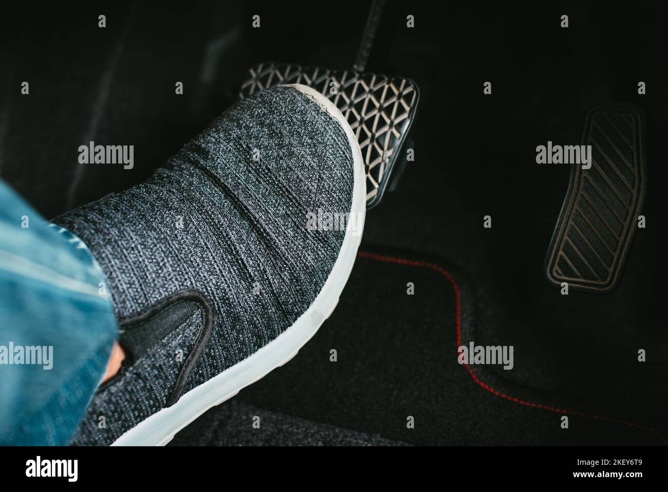 Close up the foot pressing brake pedal of a car. Driver stopping the ...