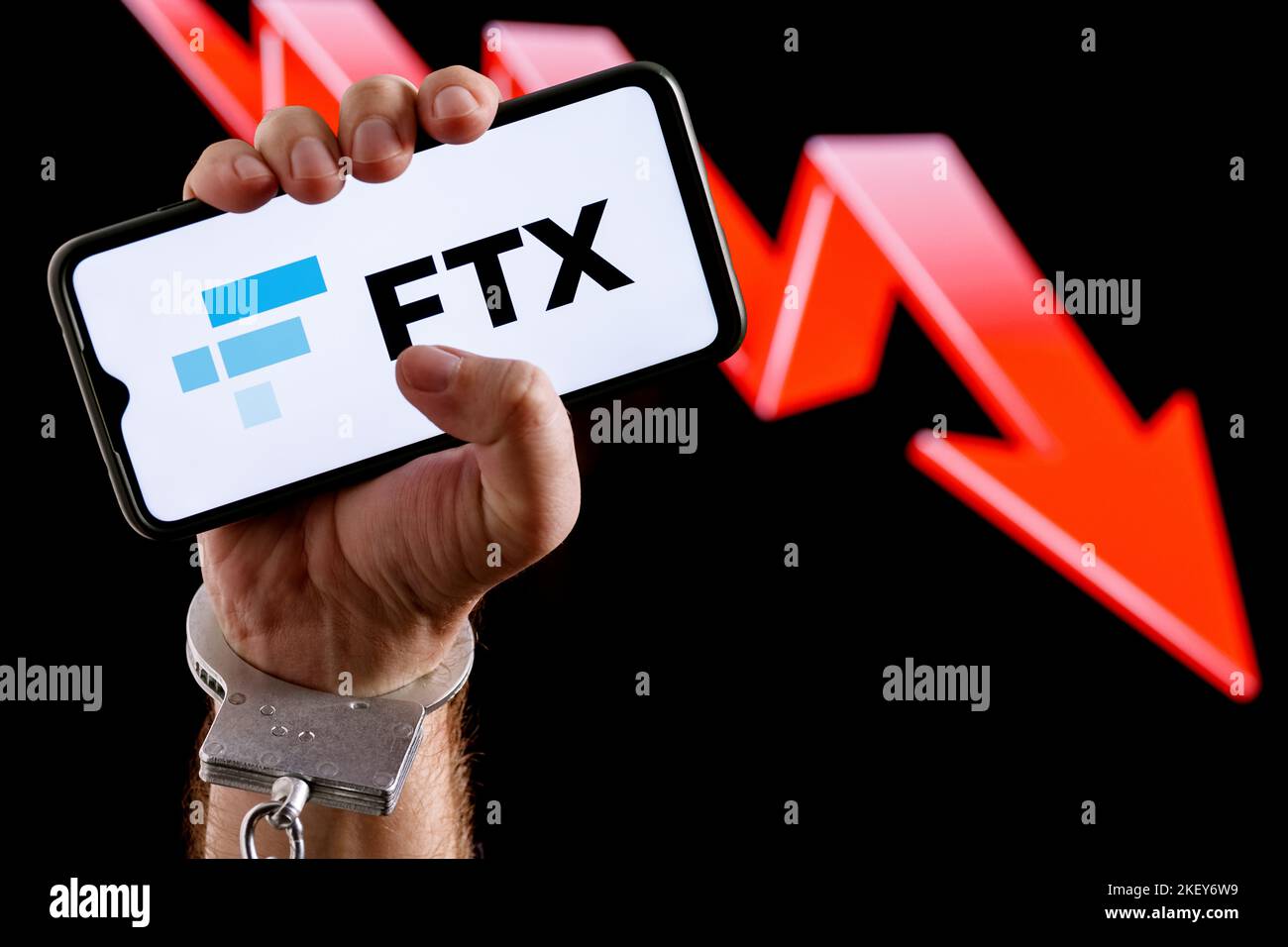 FTX is cryptocurrency exchange. Handcuffed hand squeeze smartphone with FTX logo on screen ...