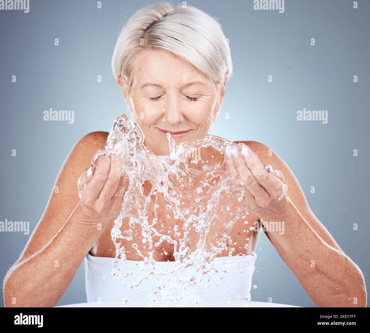 Water, splash and senior woman in studio for natural, cosmetic and facial routine for hygiene ...