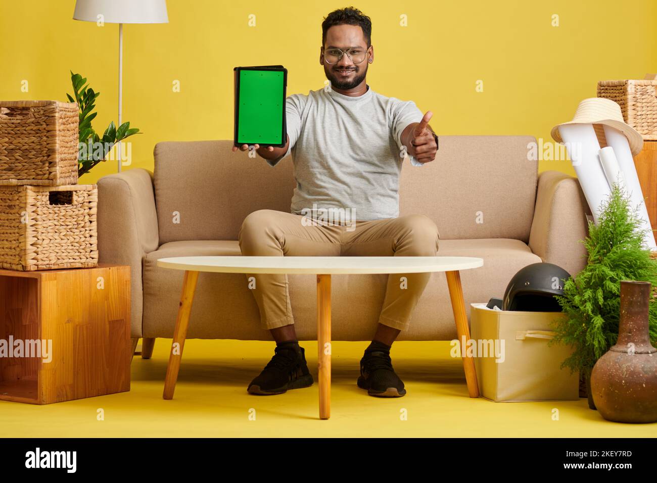 Joyful man showing tablet computer with green screen and making thumbs ...