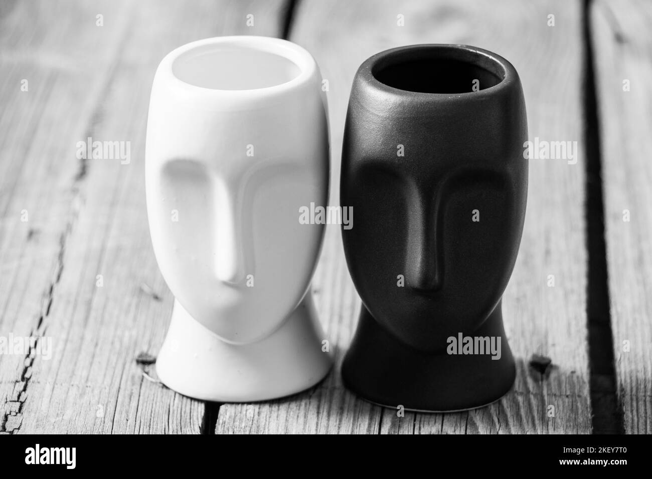 Sculpture of two faces black and white stands on a wooden table ...