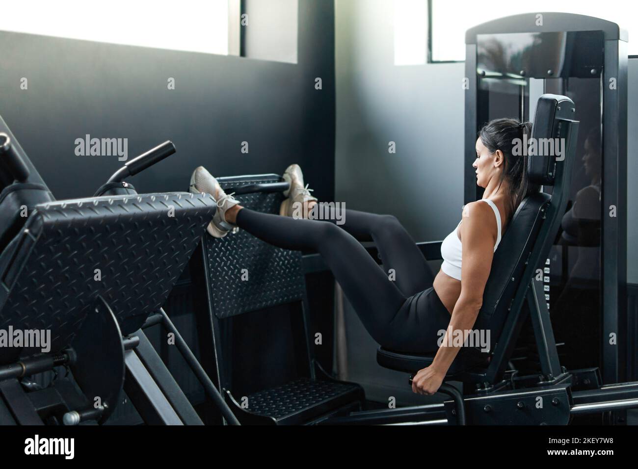 fitness woman performing exercises on a leg simulator Stock Photo - Alamy