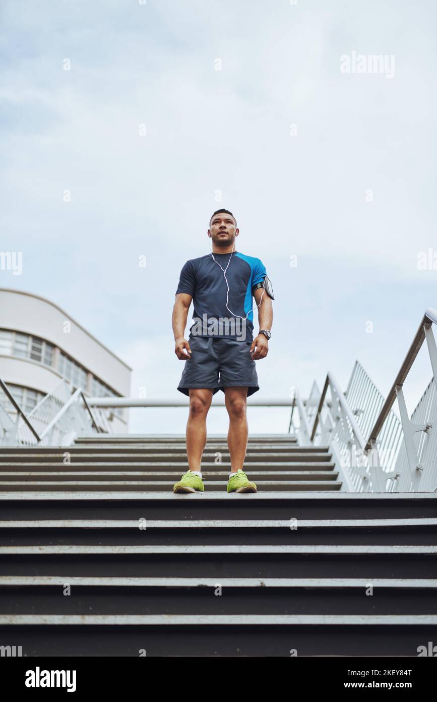 Time to get the blood pumping. Low angle shot of a male runner standing ...
