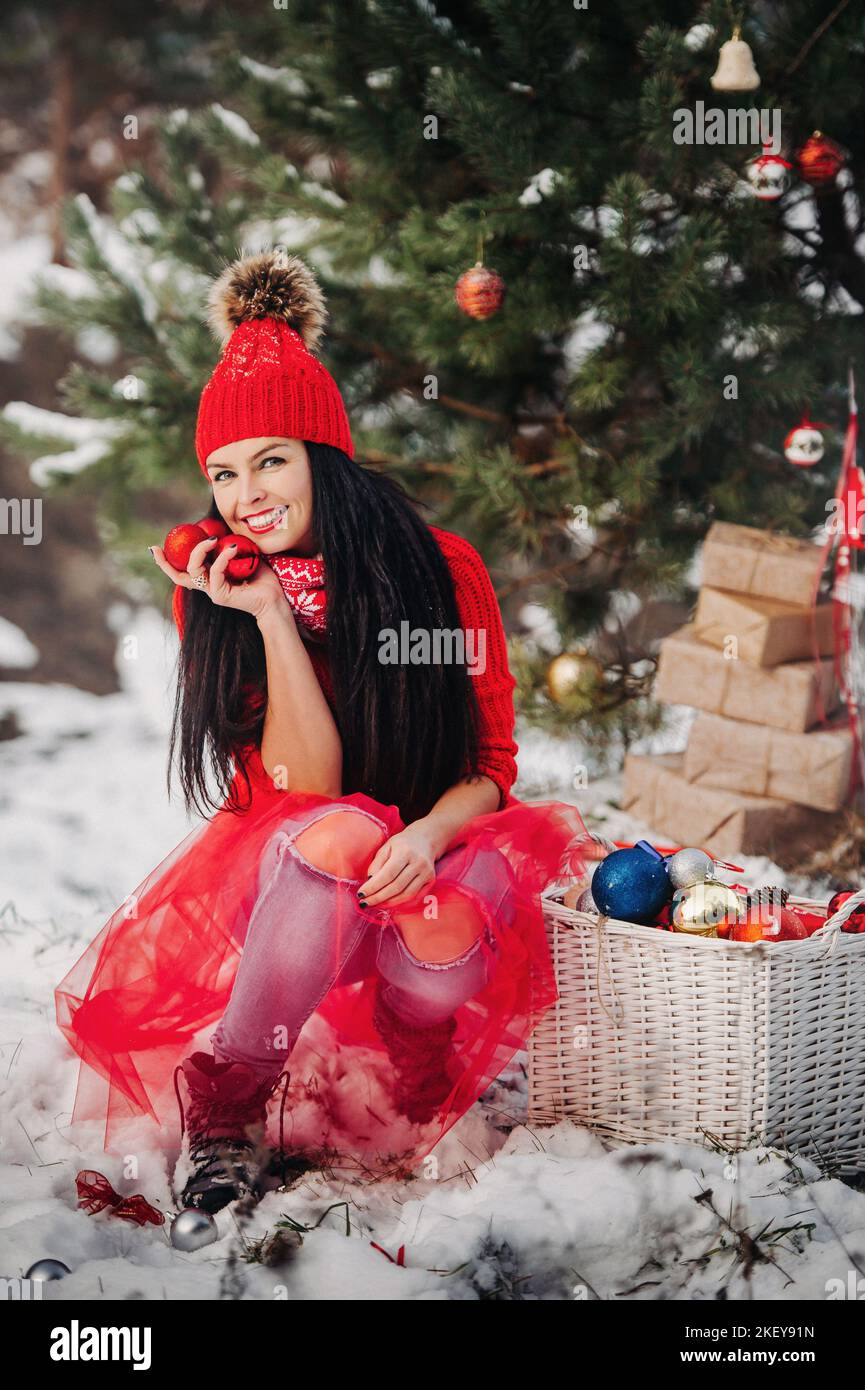 A girl in red clothes with Christmas balloons in her hands is sitting ...