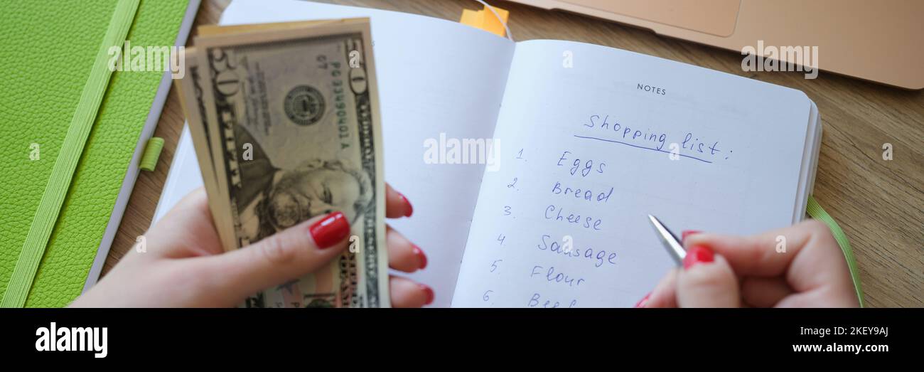 Woman makes shopping list and holds money Stock Photo - Alamy