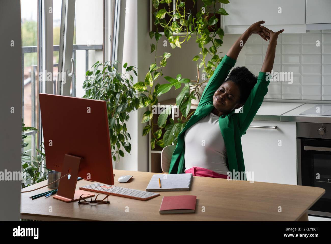 Tired young African woman remote worker doing stretching exercises and ...