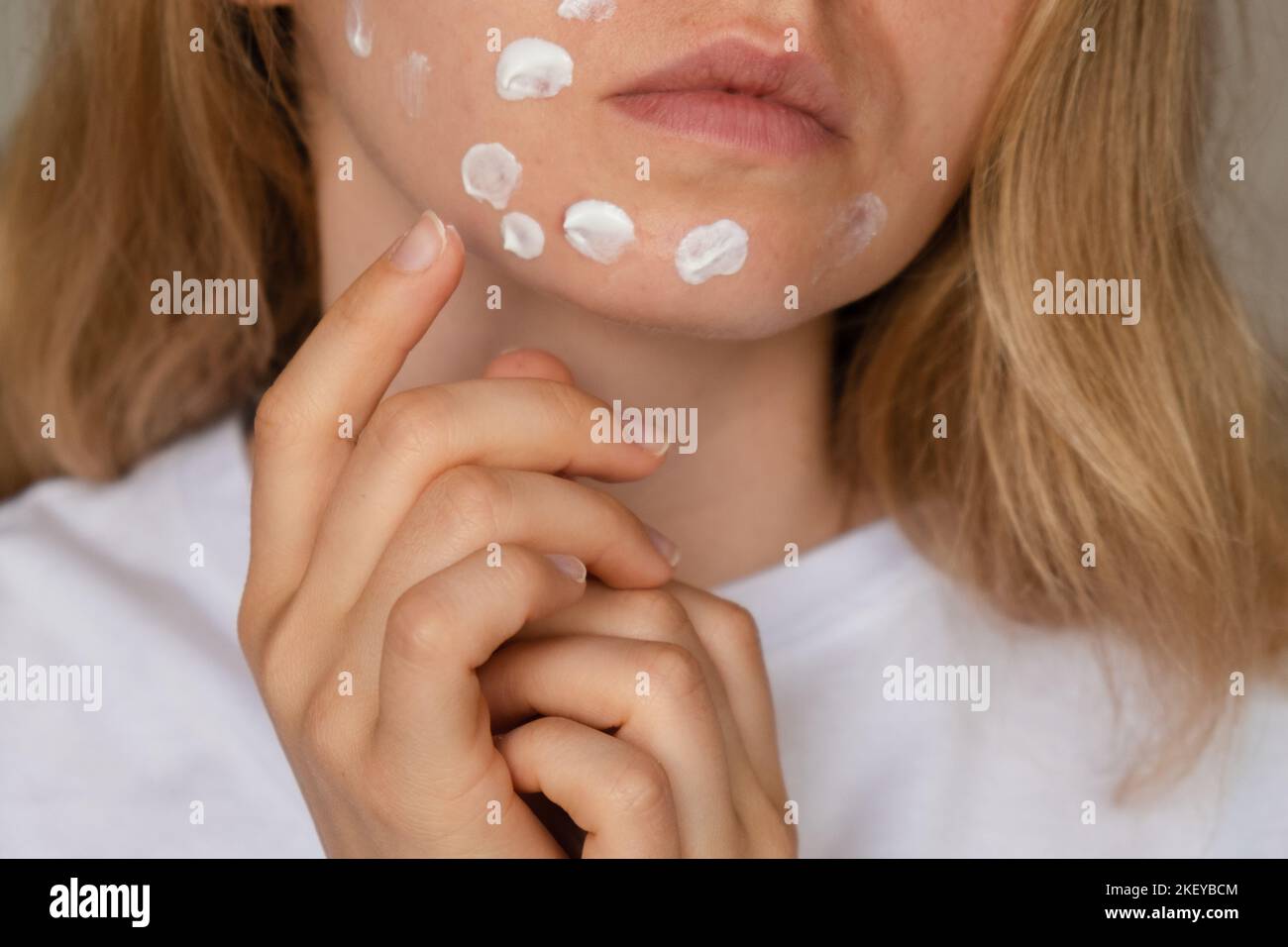 Unrecognizable woman applies makeup, cream serum cure for acne on face ...